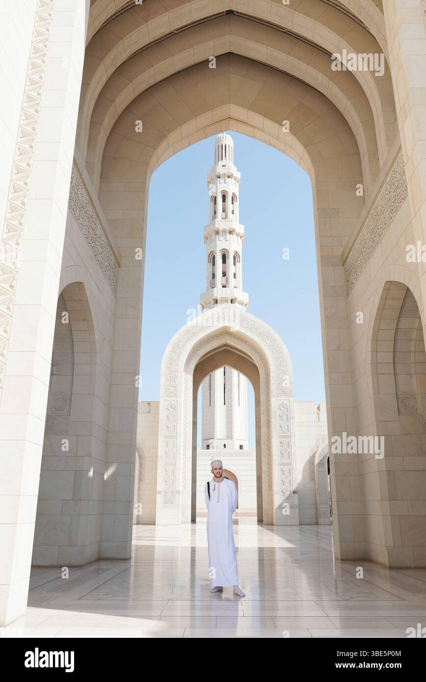 A man in traditional Omani attire stands under an arch at the Sultan ...