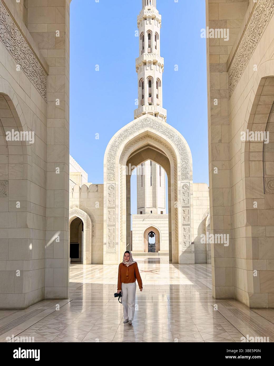 A woman wearing an headscarf walks through the grand architecture of ...