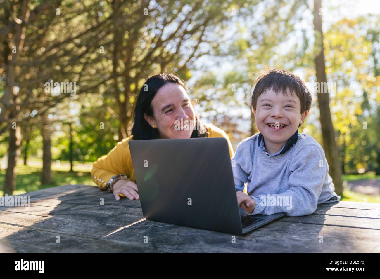 A smiling boy with Down syndrome and his mother enjoying a learning ...