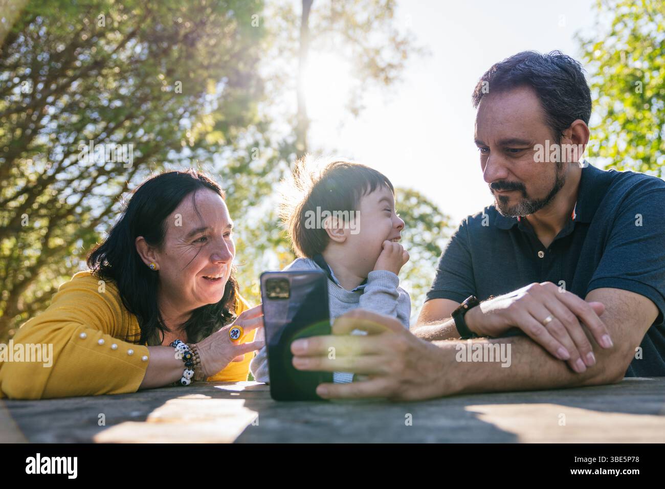 A family shares a happy moment in the sunshine, with a child with Down ...