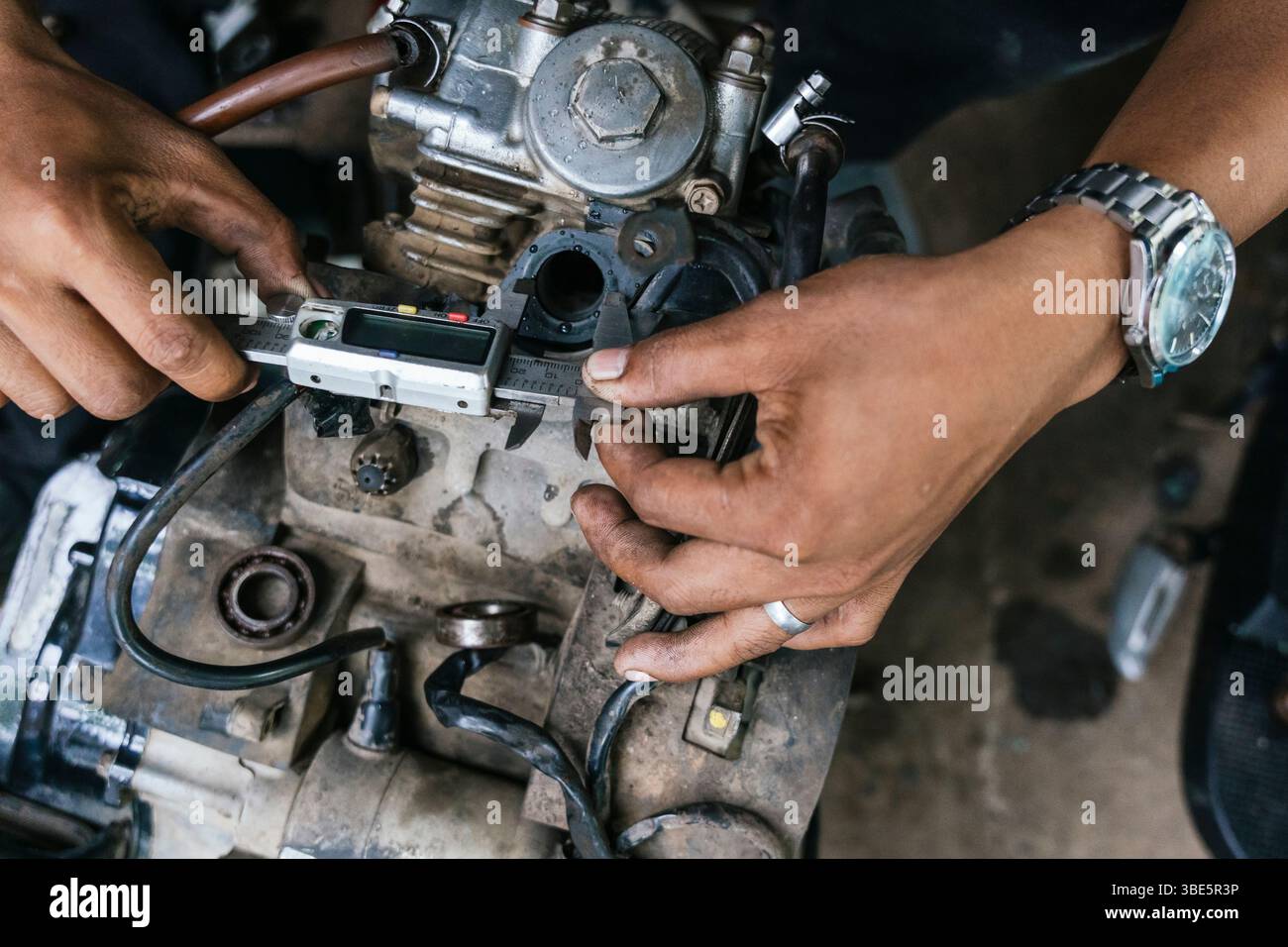Hands of a mechanic using a caliper to measure parts of a motorcycle ...