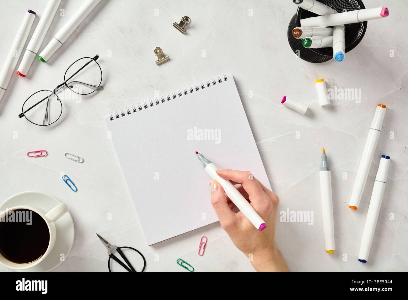 Top view of an artist cropped unrecognizable hand in a workspace features sketching markers, a ...