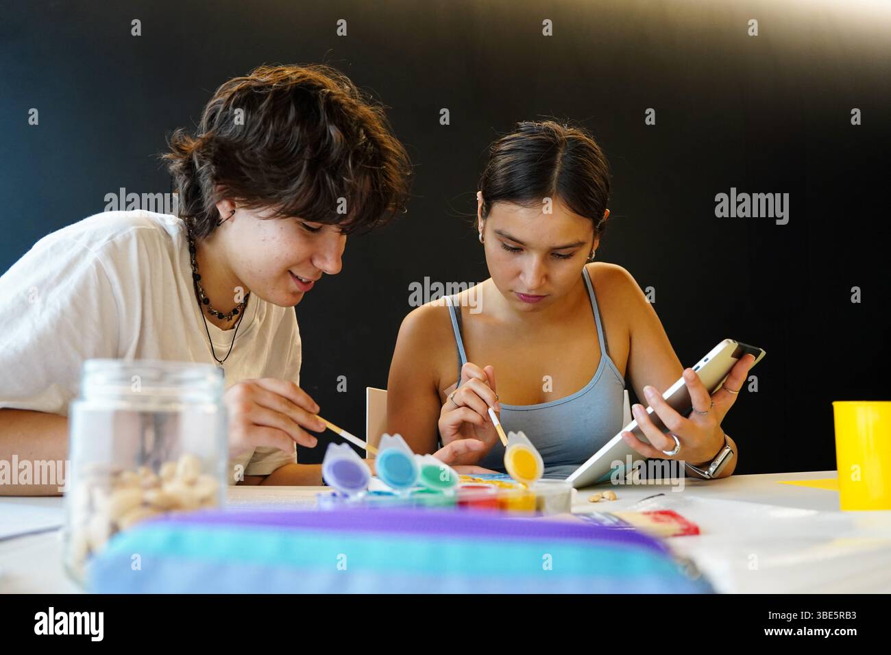 Two teenagers, a non-binary individual and a female, are deeply engaged ...