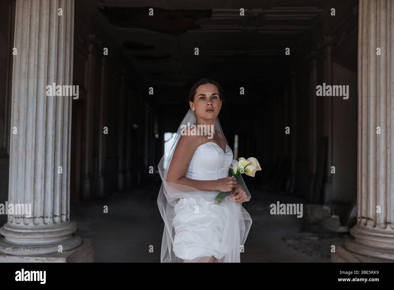 A bride in a stunning white gown poses gracefully in an ancient villa ...