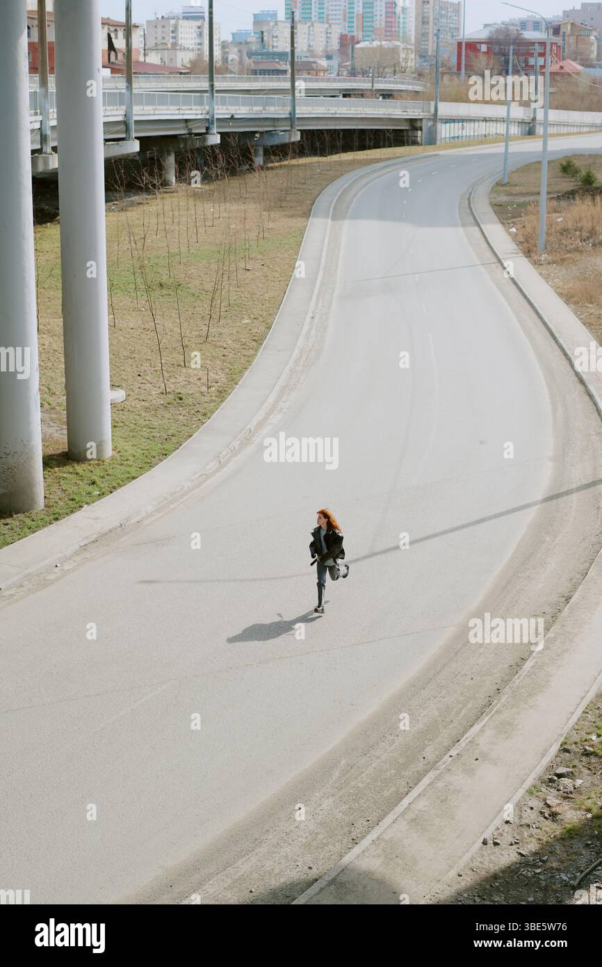 A solitary figure is seen walking on an empty, curved road near an ...