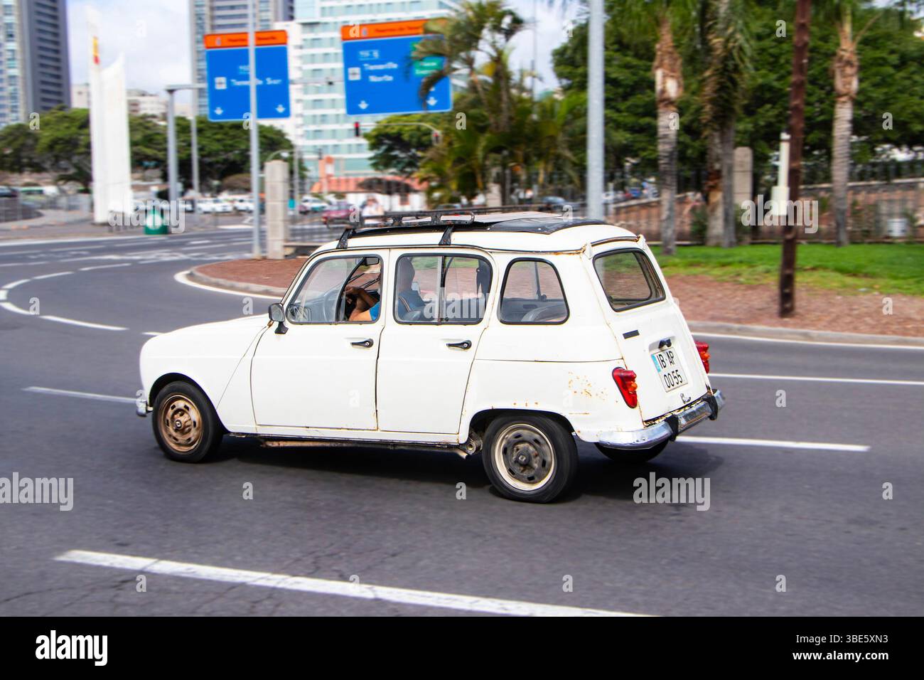 Vintage white Renault 4 car driving on a city street with blue traffic ...