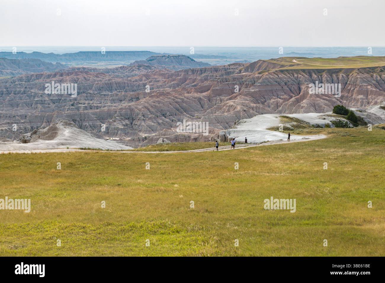 Park visitors walk along the path at the edge of the Badlands National ...