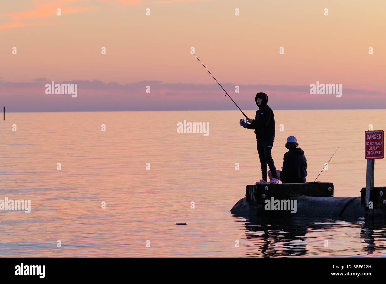 Silhouette of young adults ignoring danger sign while fishing on storm ...