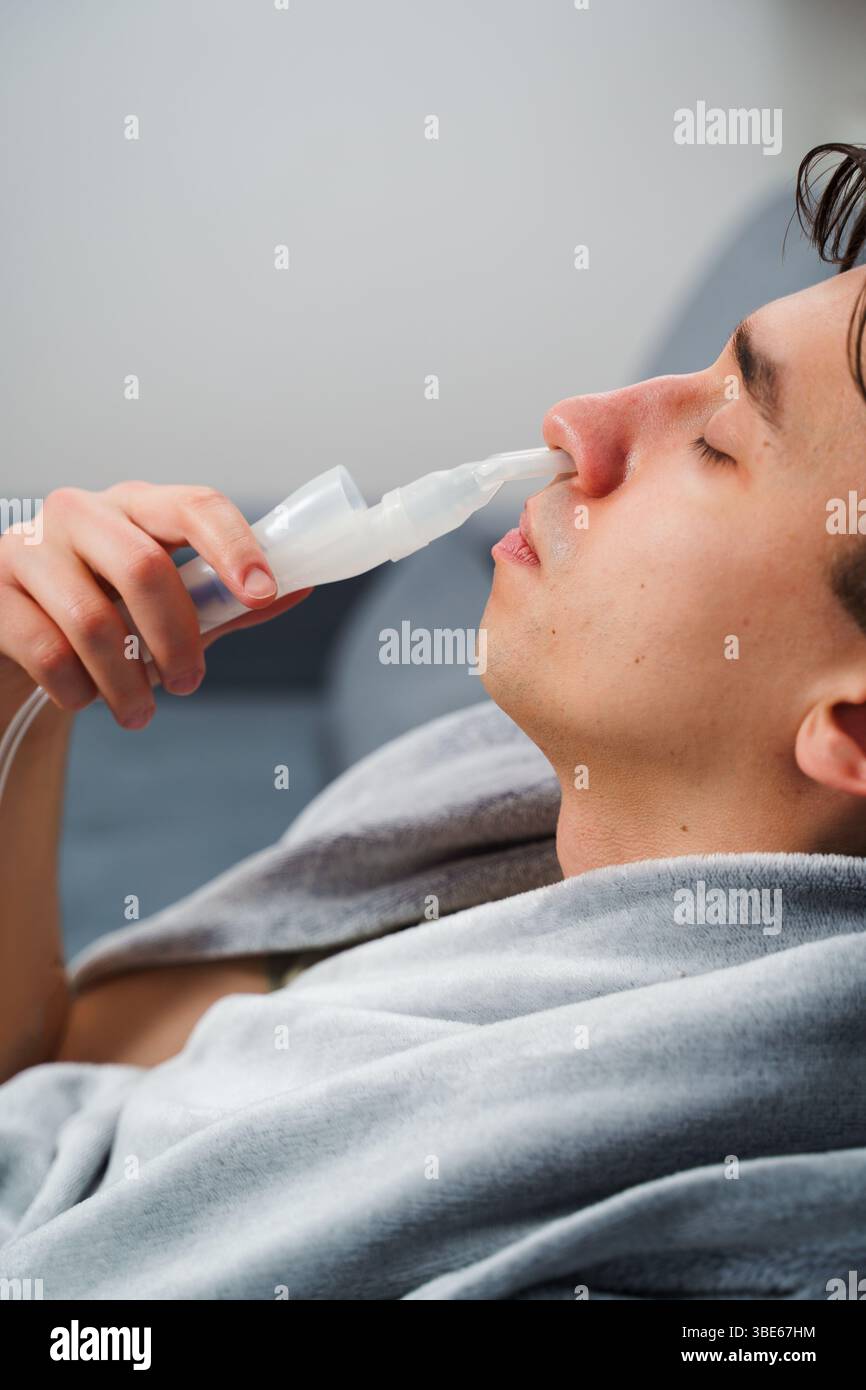 Young man with asthma attack breathing with inhaler in the bad. Doing ...