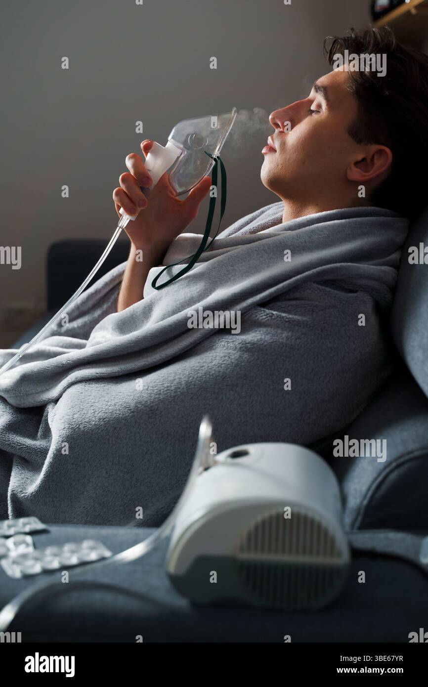 Using compressor nebulizer for disease treatment at home. Man inhaling ...
