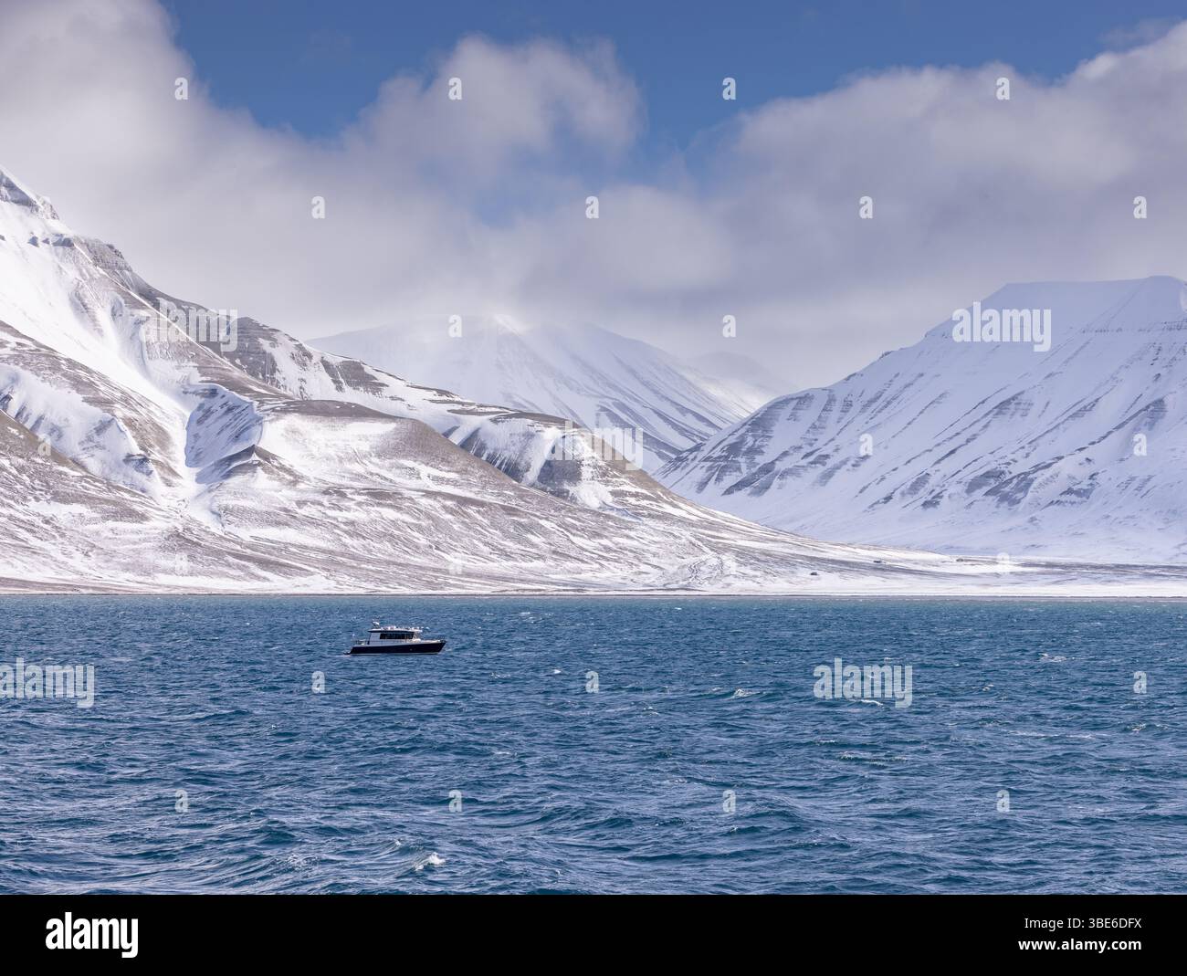 A small motorboat crosses the cold waters off Svalbard, Norway, with ...