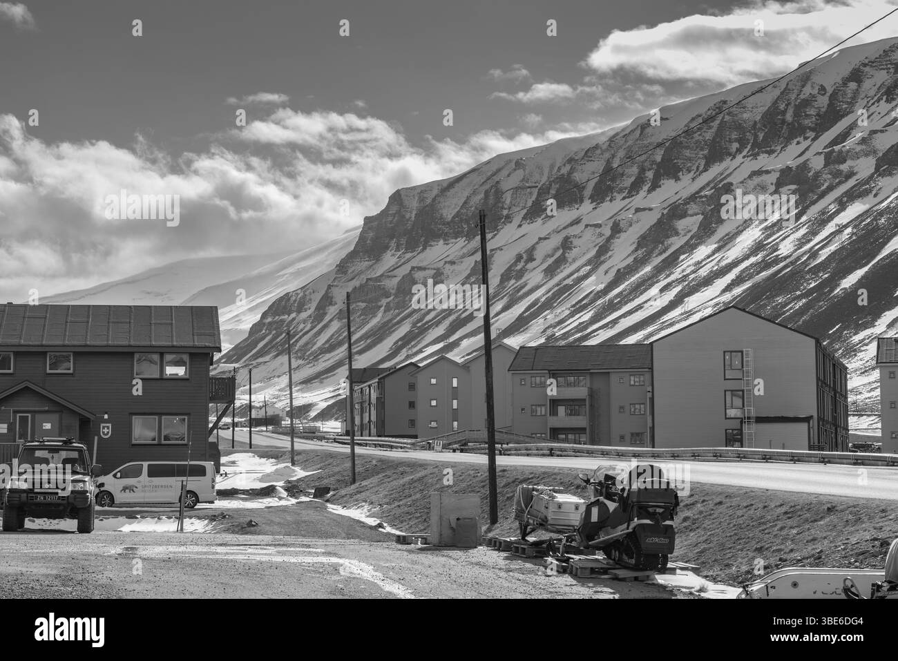 Black and white image of Longyearbyen homes, snowmobiles, and steep ...