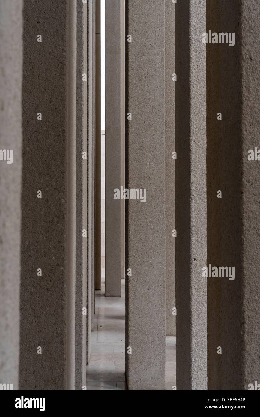 A narrow passage with textured concrete walls channels daylight inside ...