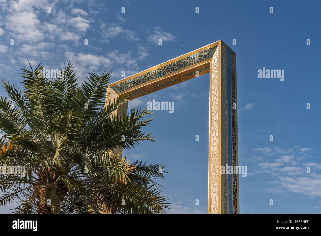 The Frame rises above lush palm trees with intricate gold patterns ...
