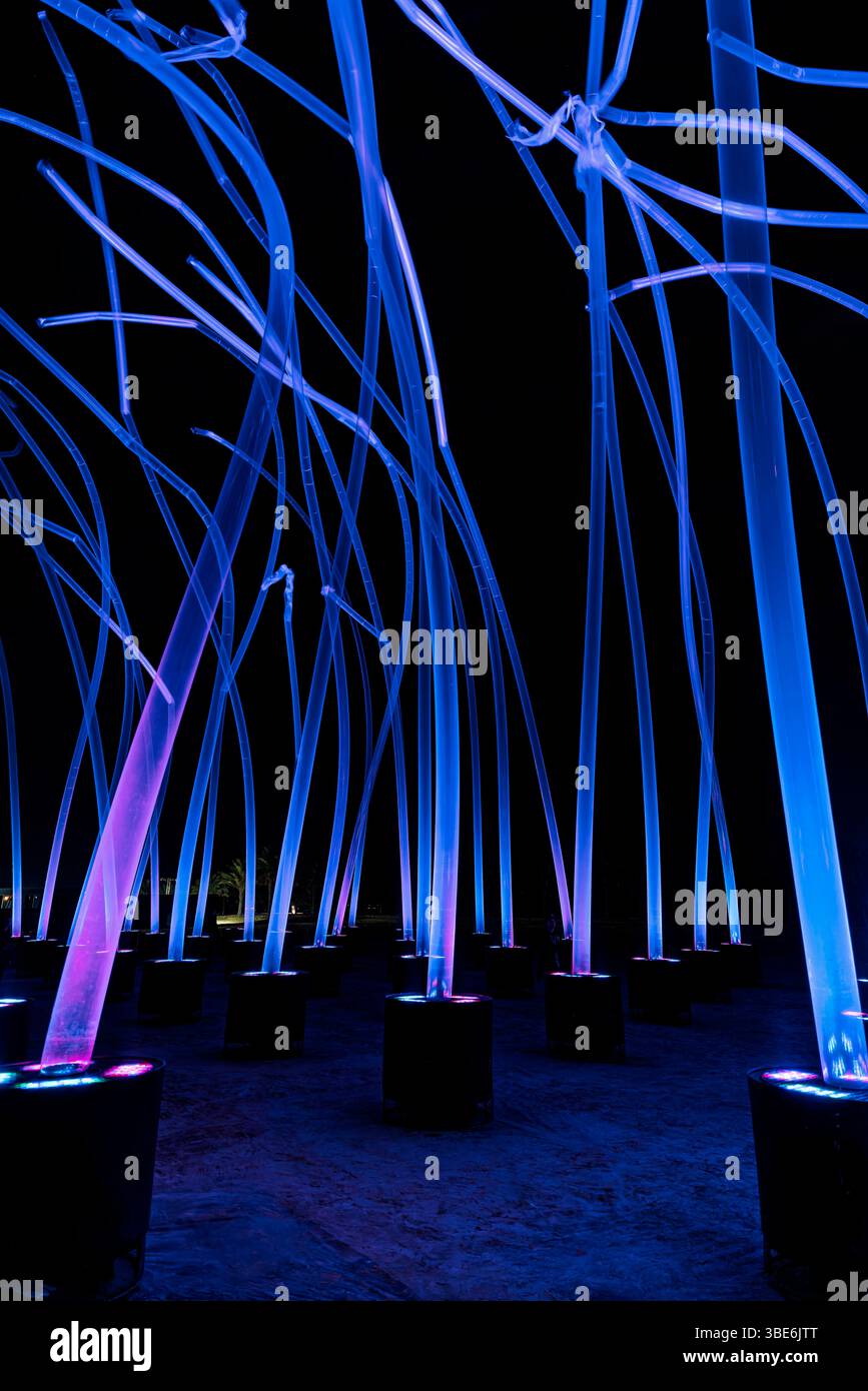 Tall illuminated white and blue pillars bend upwards against a dark sky ...