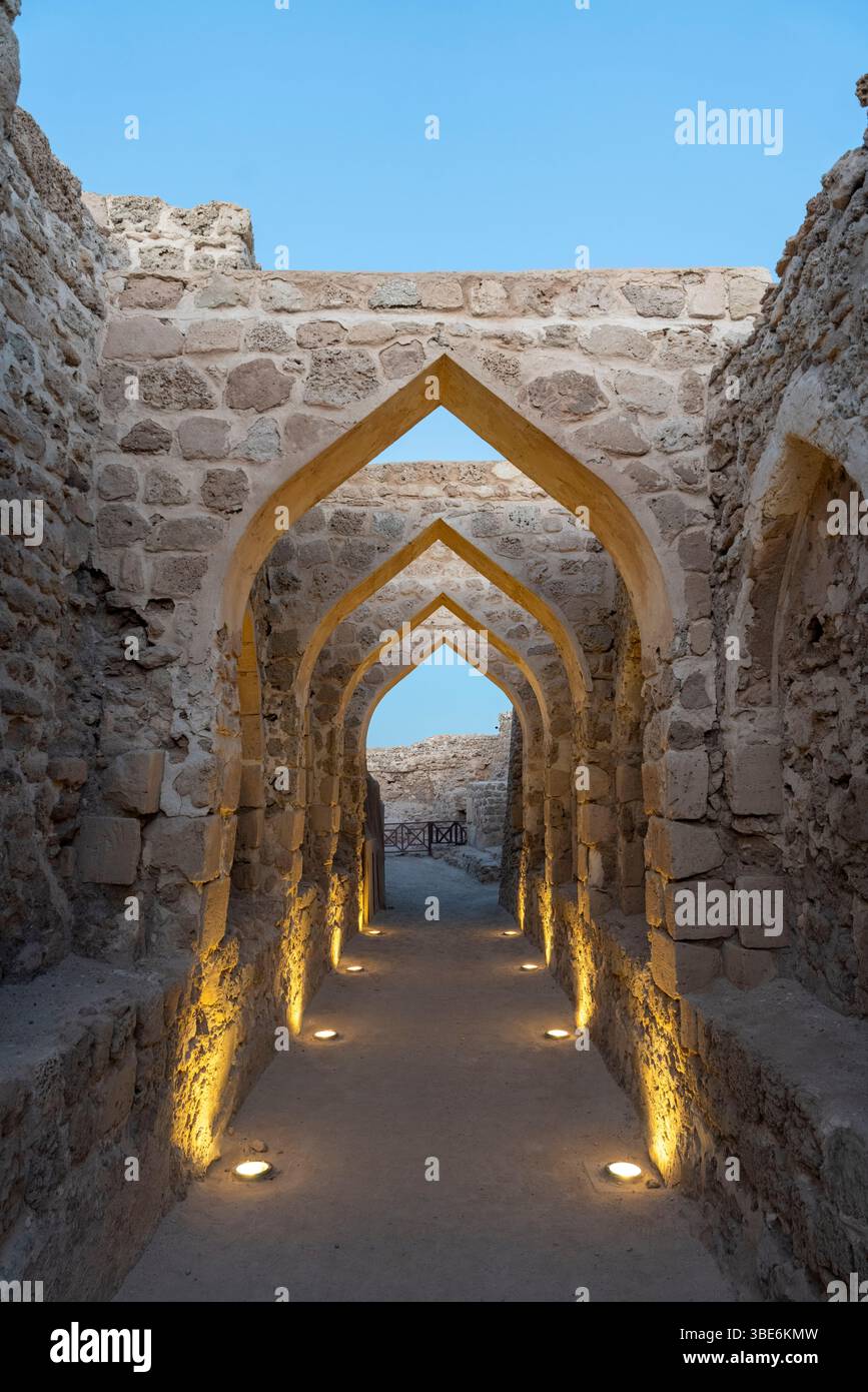 A row of illuminated stone arches creates a glowing passageway at Qalat ...