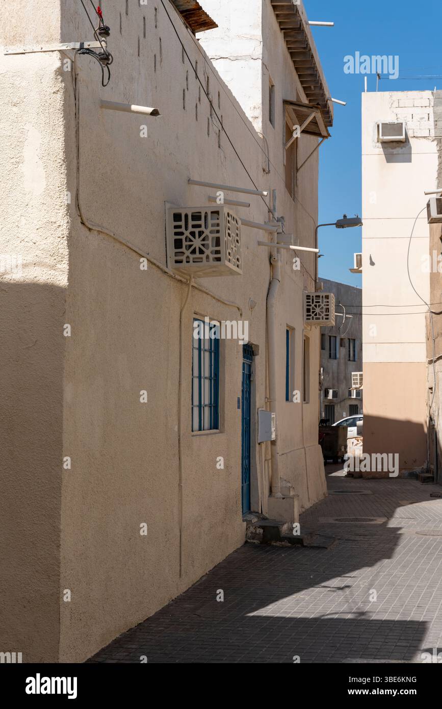 Narrow shaded alley lined with cream walls and windows highlights ...