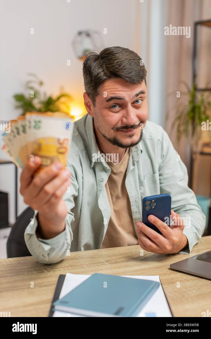Planning family budget. Smiling Caucasian man counting money euro cash ...