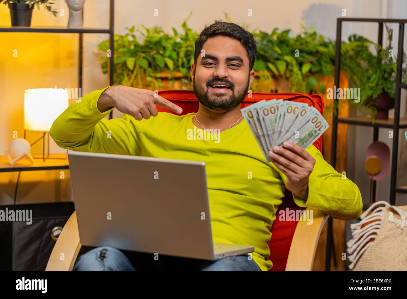 Planning budget. Rich excited Indian man counting money cash use laptop ...