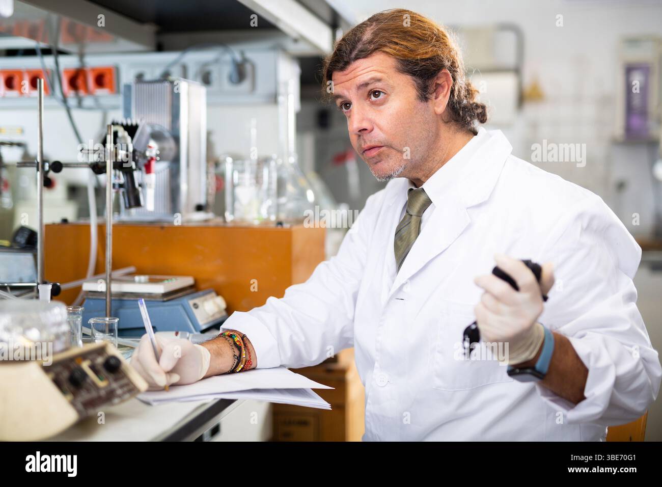 Male scientist engaged in research in chemical laboratory, noting ...