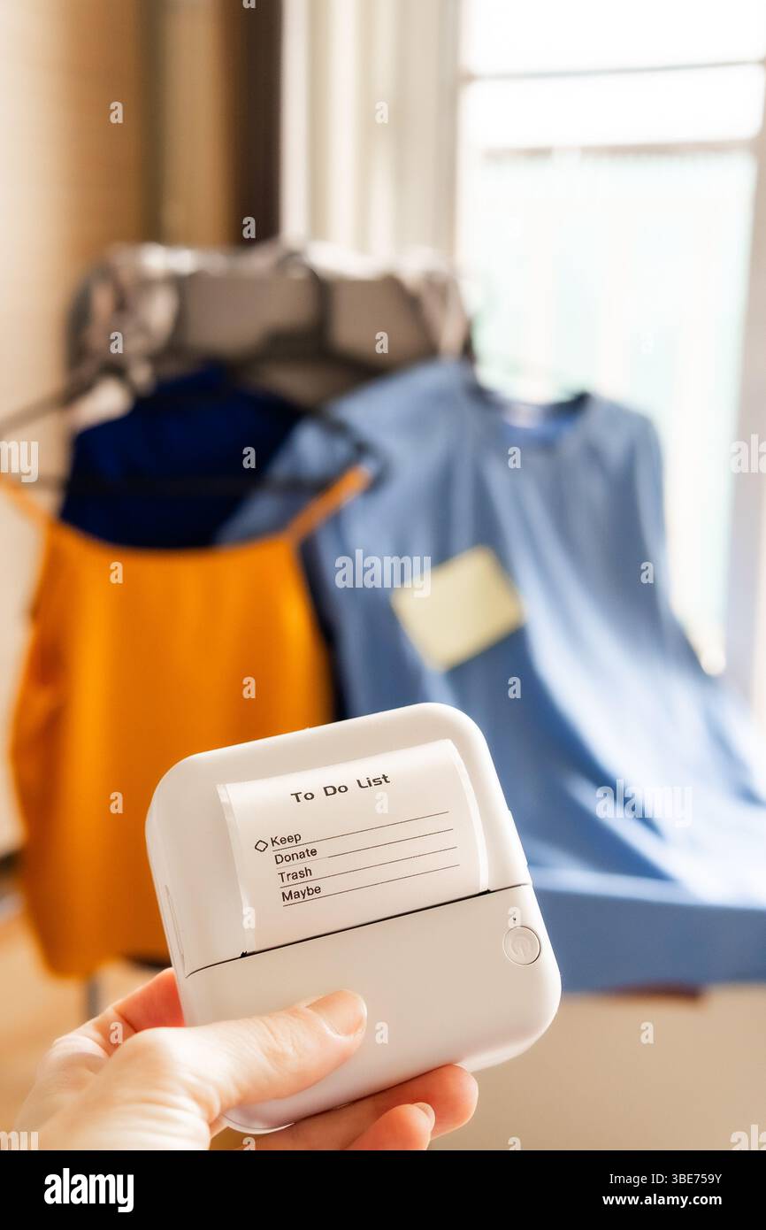 Hand holding mini thermal printer with clothing decluttering checklist ...