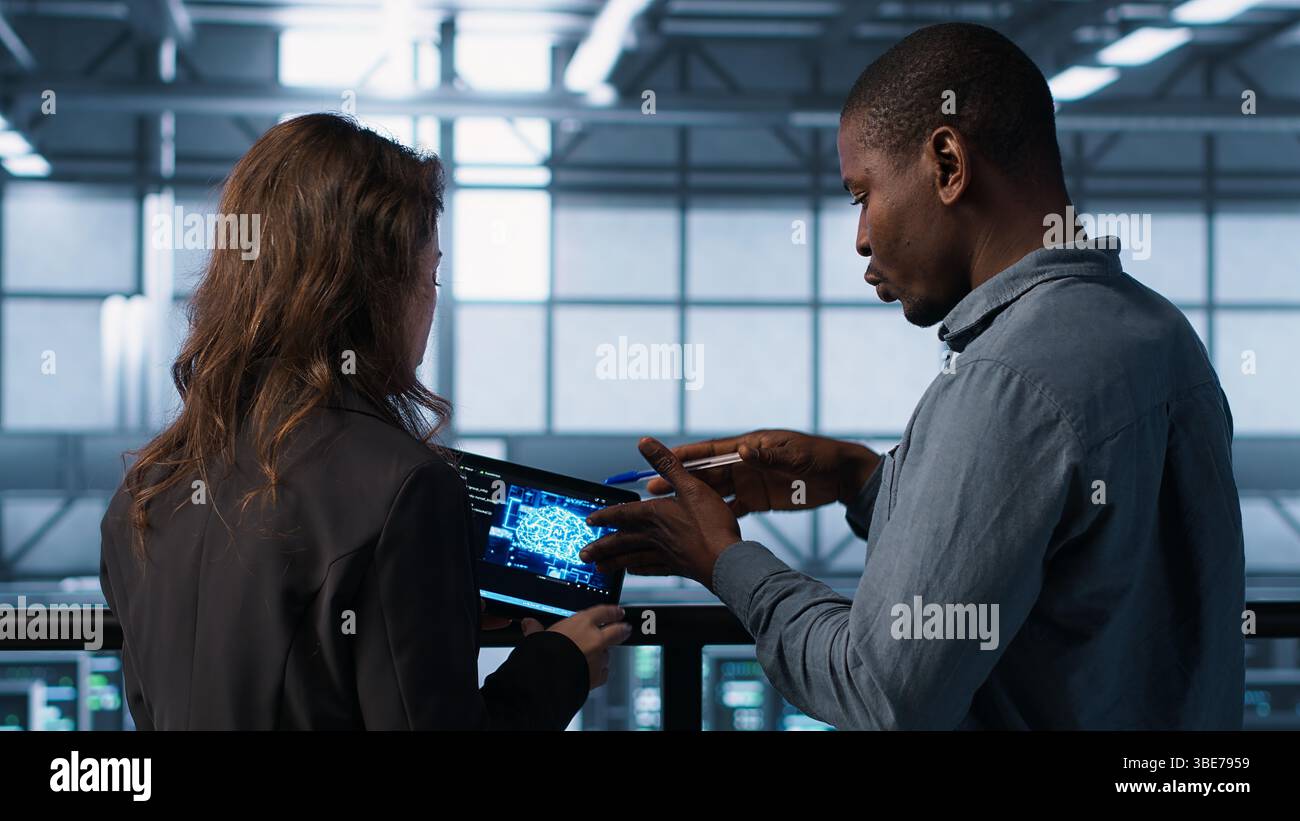 Data center system administrators using artificial intelligence neural networks tech on tablet ...