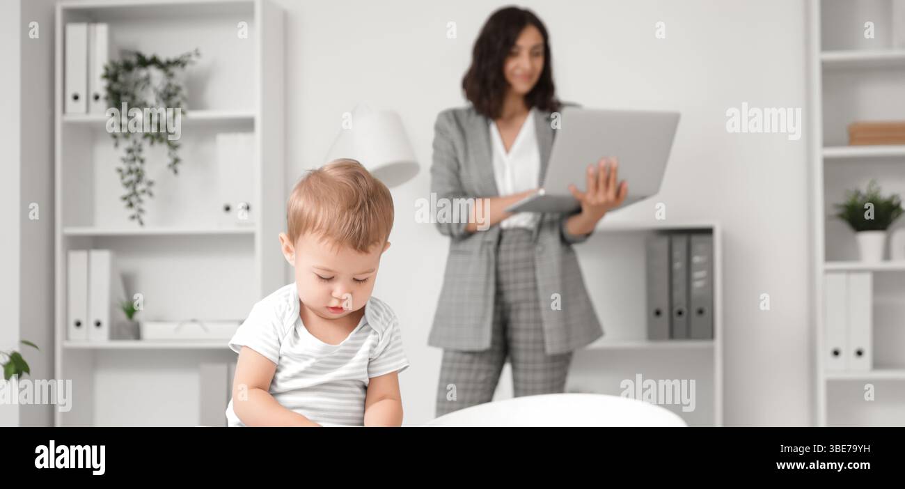 Cute little baby and his mother working in office Stock Photo - Alamy