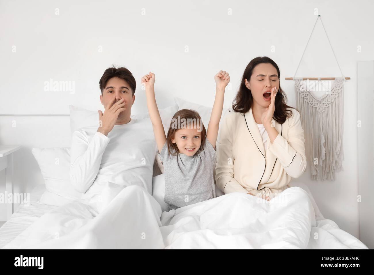 Little girl with her sleepy parents under blanket in bedroom Stock ...