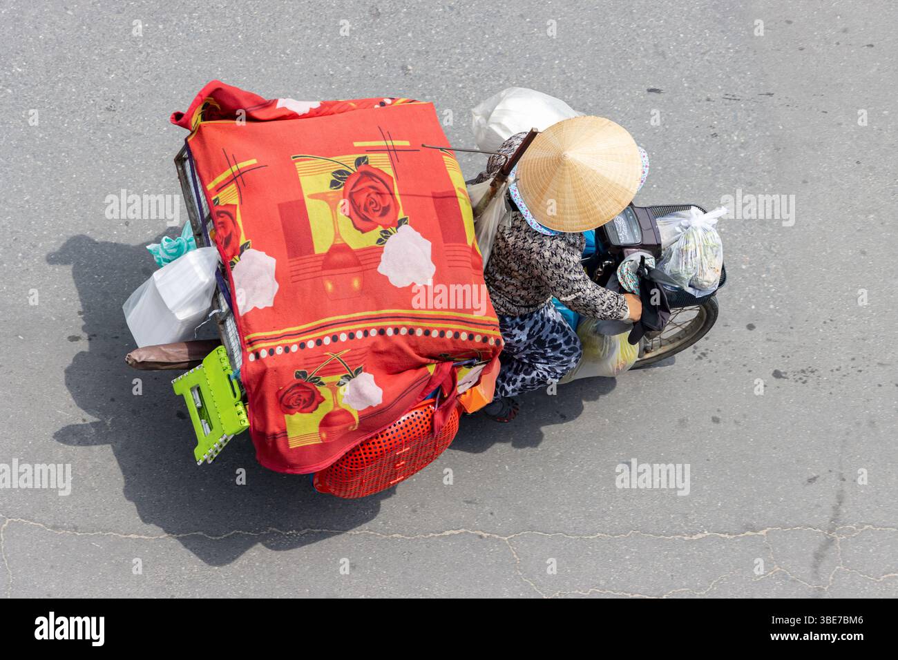 A street food vendor rides a fully loaded motorbike with a stall and ...