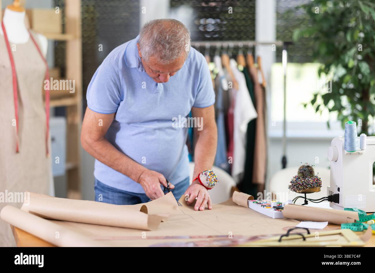 Elderly male tailor cutting out pattern from paper Stock Photo - Alamy