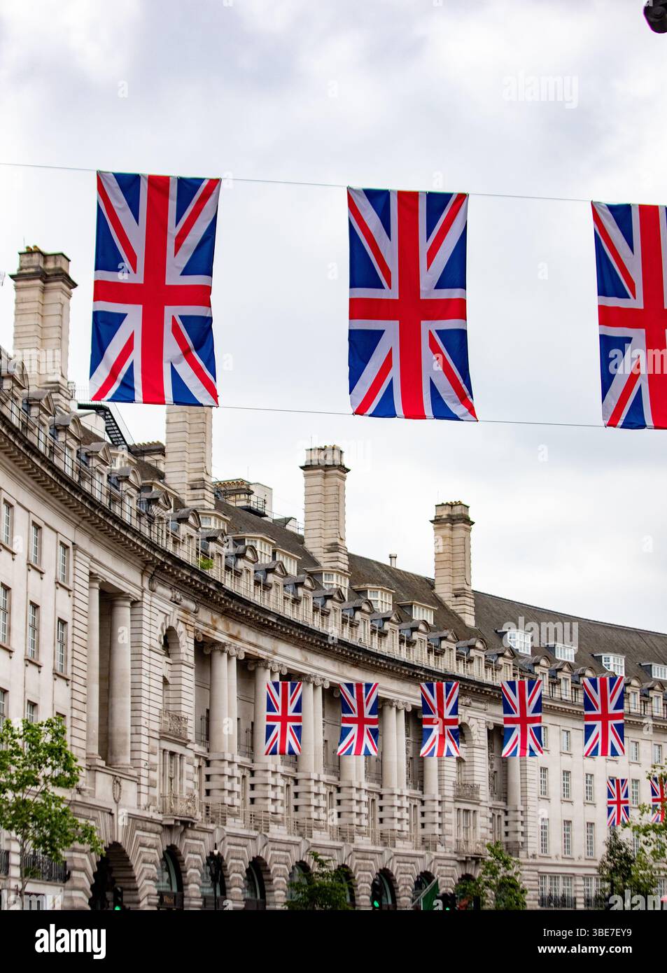 Union Jack flags adorn a historic curved building facade in London. The ...