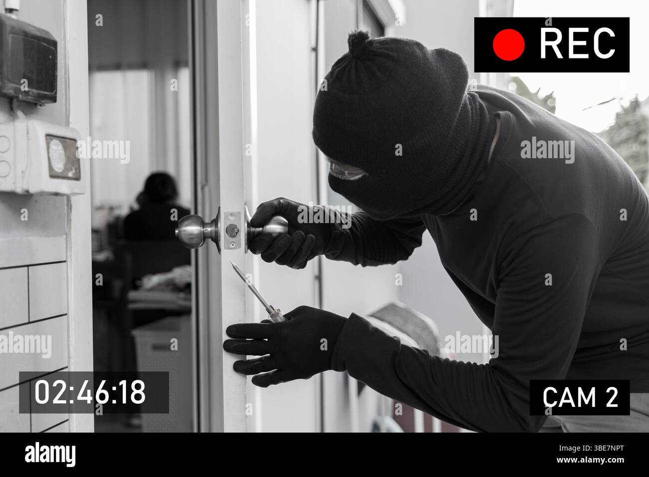 Masked burglar attempting to break into a house with a screwdriver ...