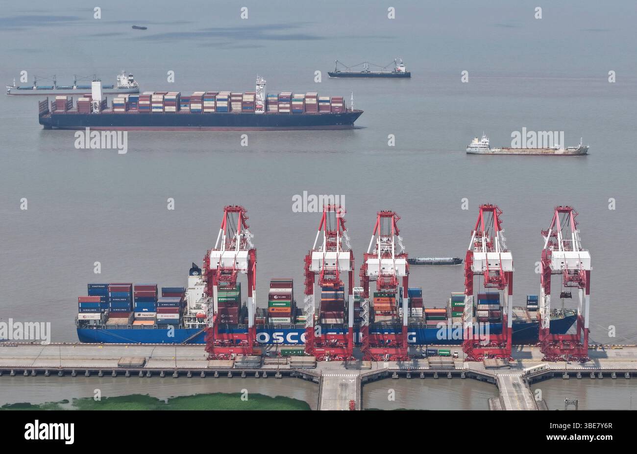A container ship sails by a container terminal in Shanghai, China ...