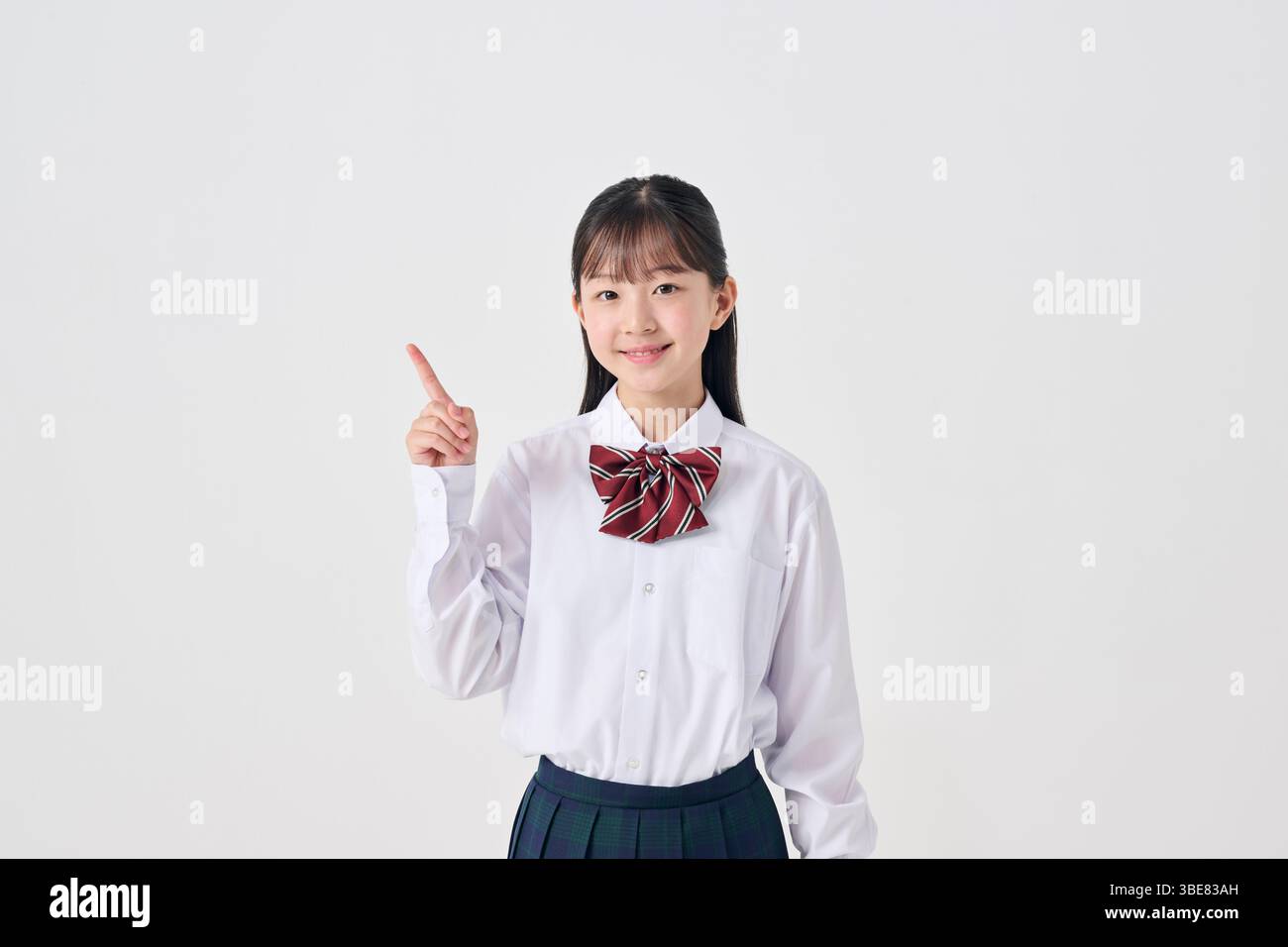 Japanese junior high school girl pointing to the left, white background ...
