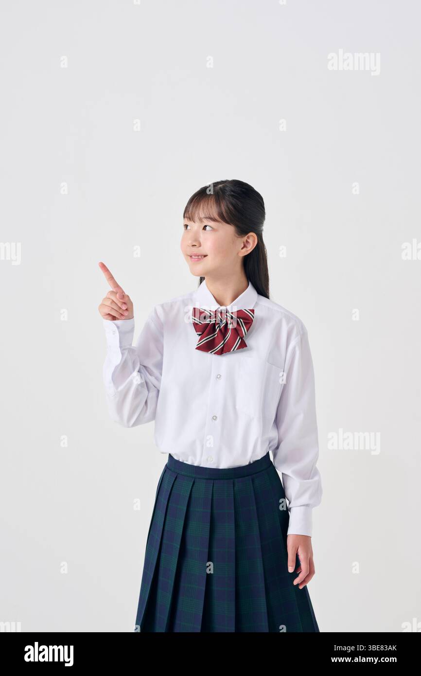Japanese junior high school girl pointing to left, white background ...