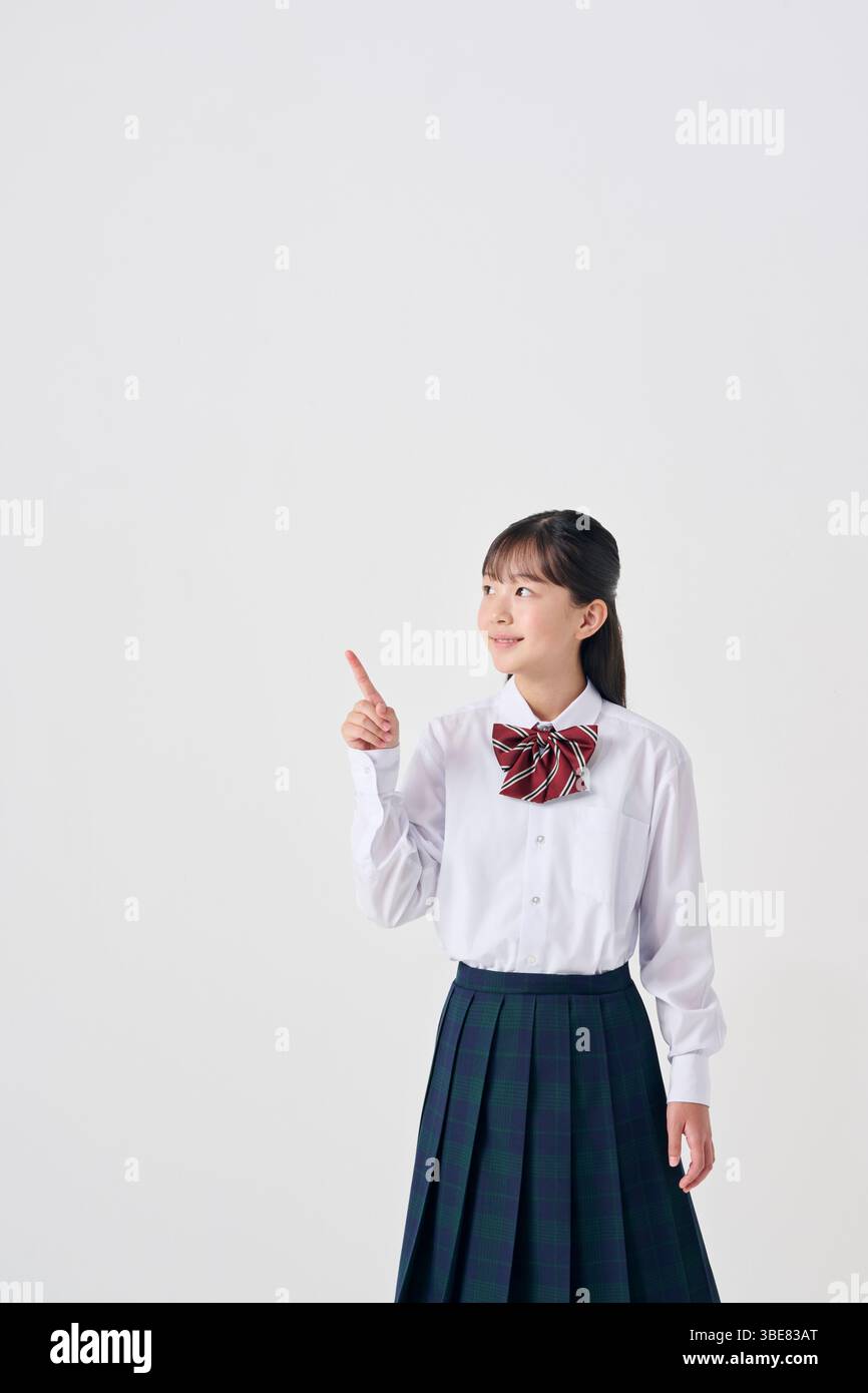 Japanese junior high school girl pointing to left, white background ...