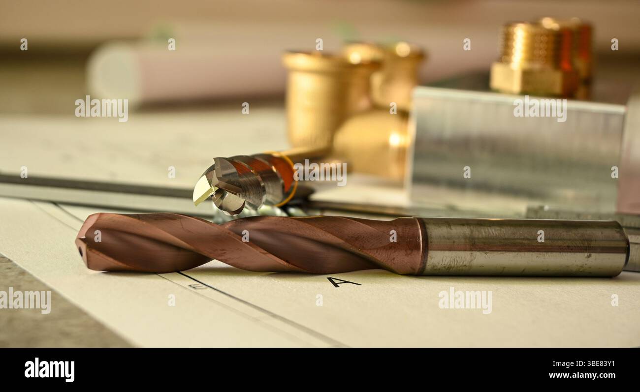 Metal drill bits, milling cutters and a caliper are laying on a ...