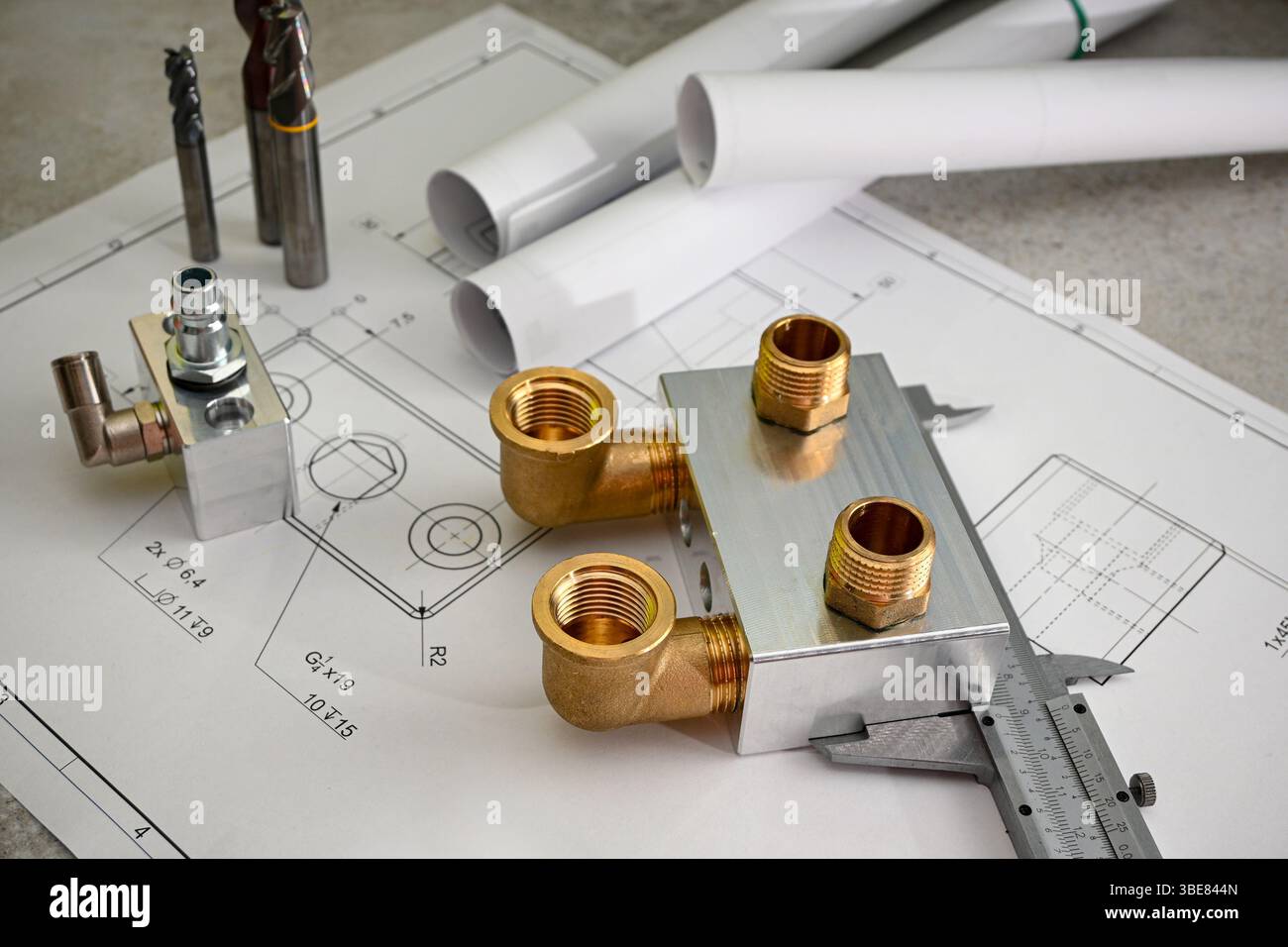 Plumbing fixture, caliper, blueprint and milling cutters lying on a ...