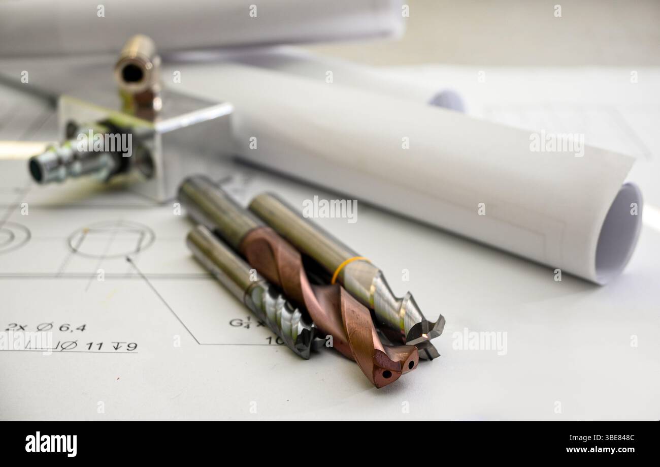 Drill bits and milling cutters are lying on a technical drawing next to ...