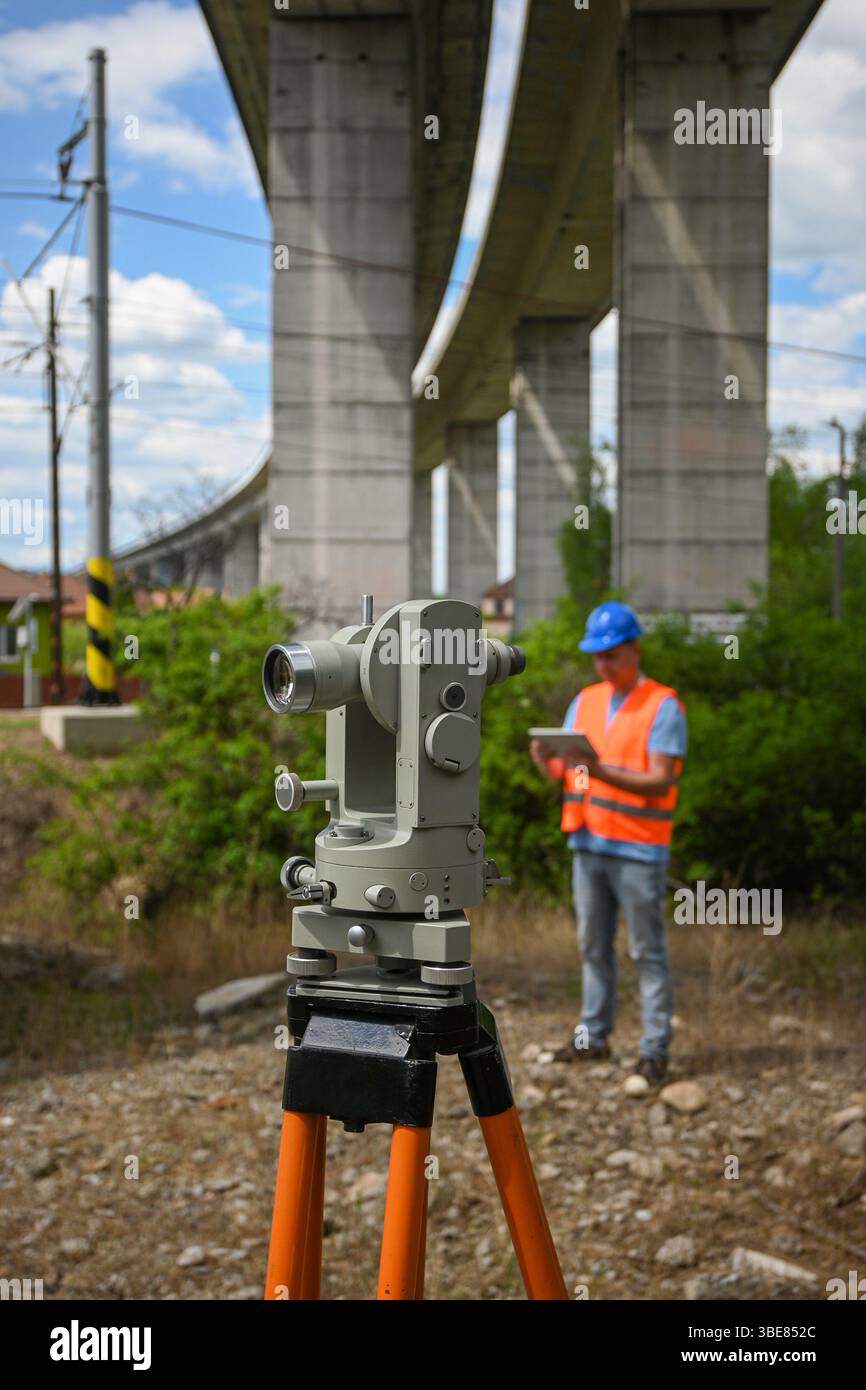 Surveyor taking measurements with theodolite near highway bridge ...