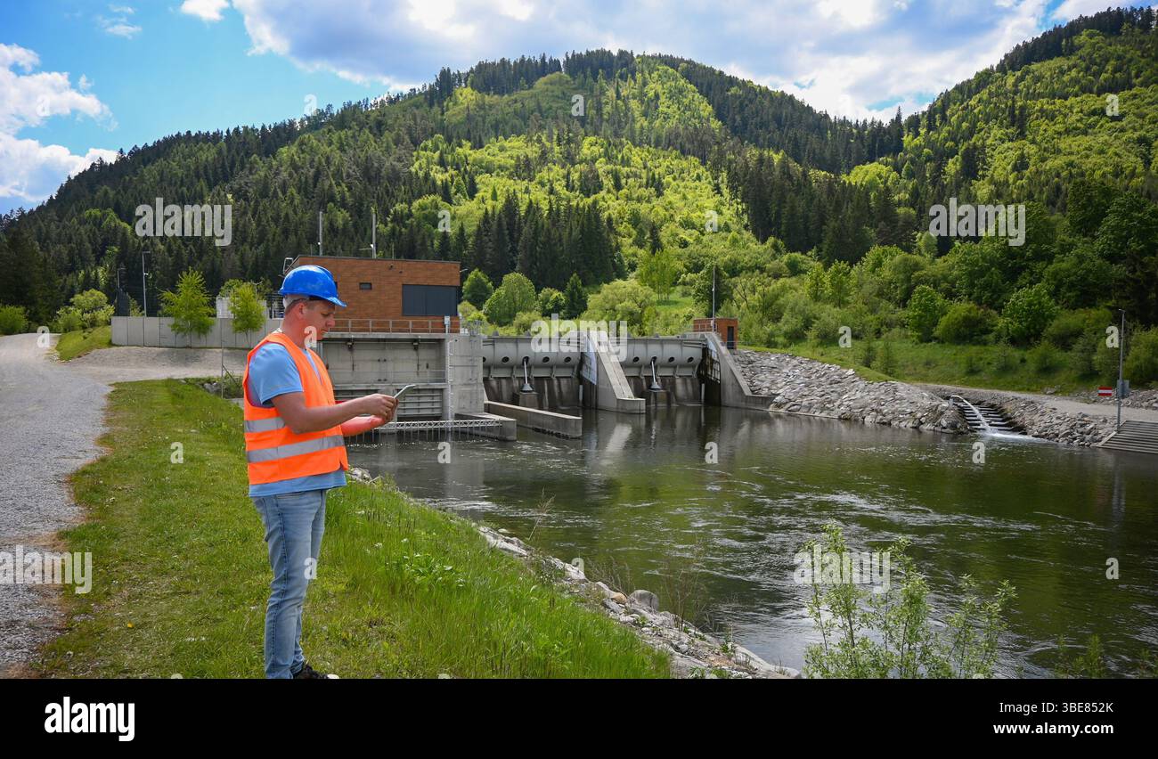 Male engineer using tablet next to a dam of a hydroelectric power plant ...