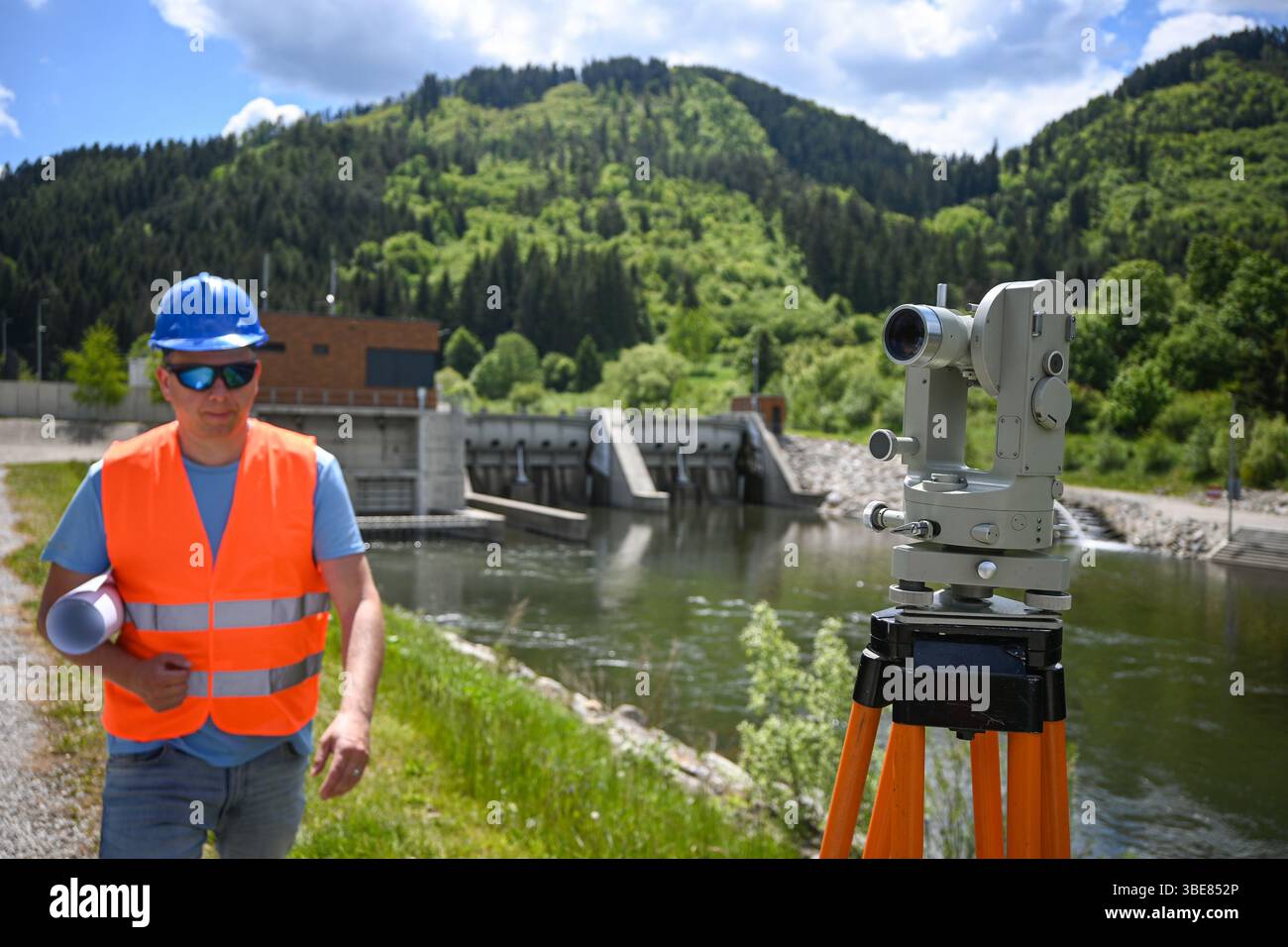 Surveyor walking near theodolite measuring water level of river at dam ...