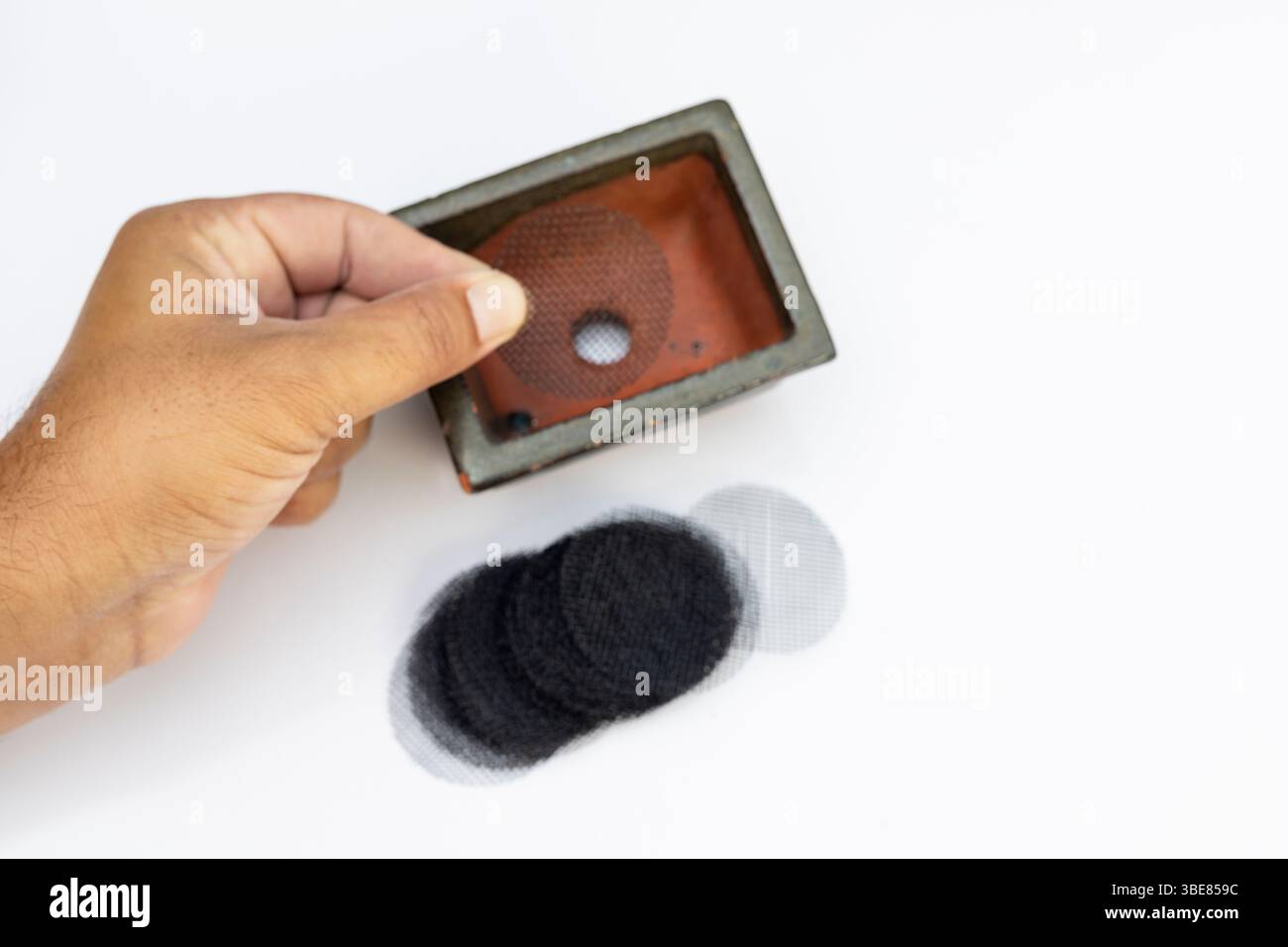 Hand placing mesh screen in bonsai pot for covering drainage hole on ...