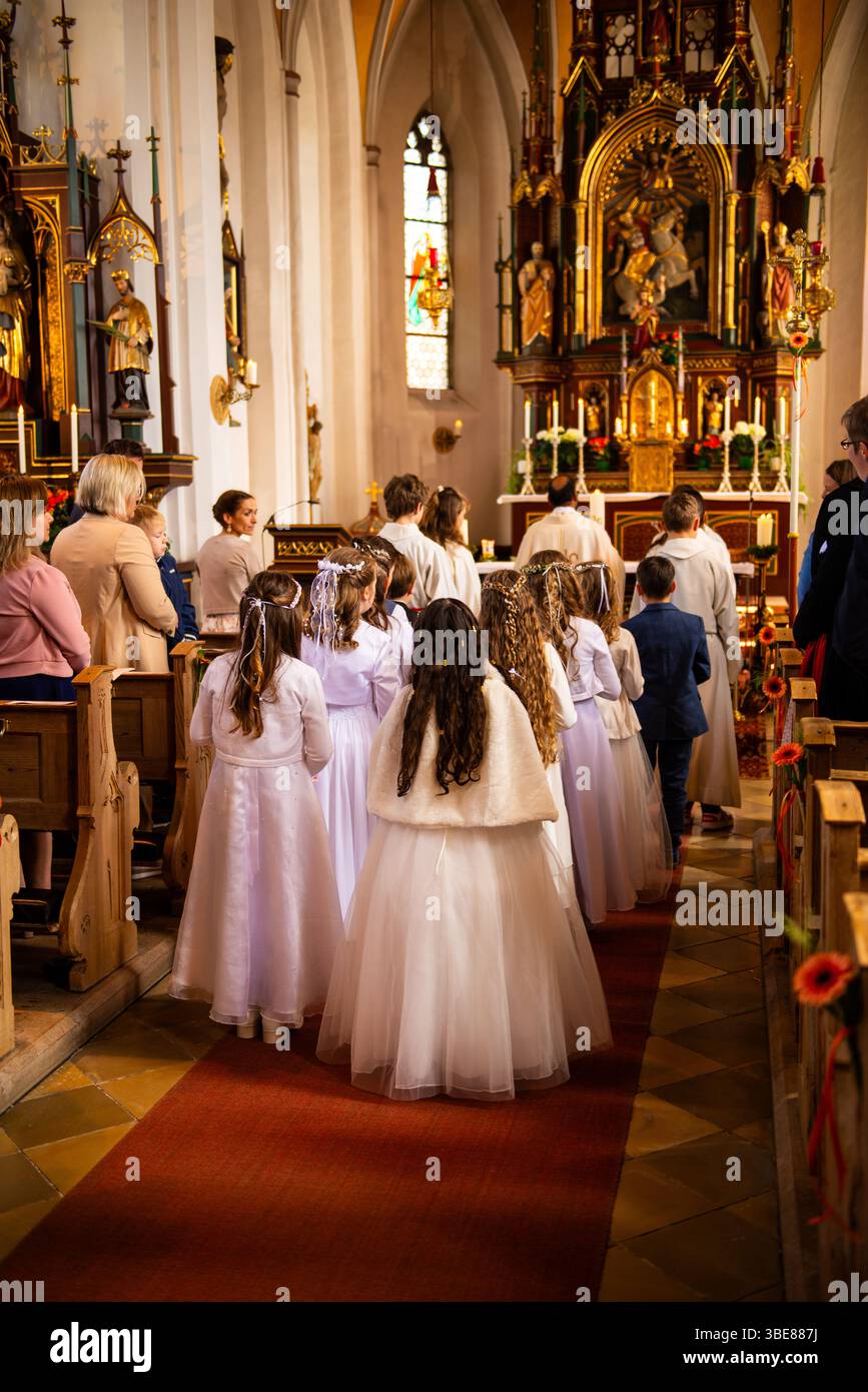 A group of children stand in church at the end of their first communion ...
