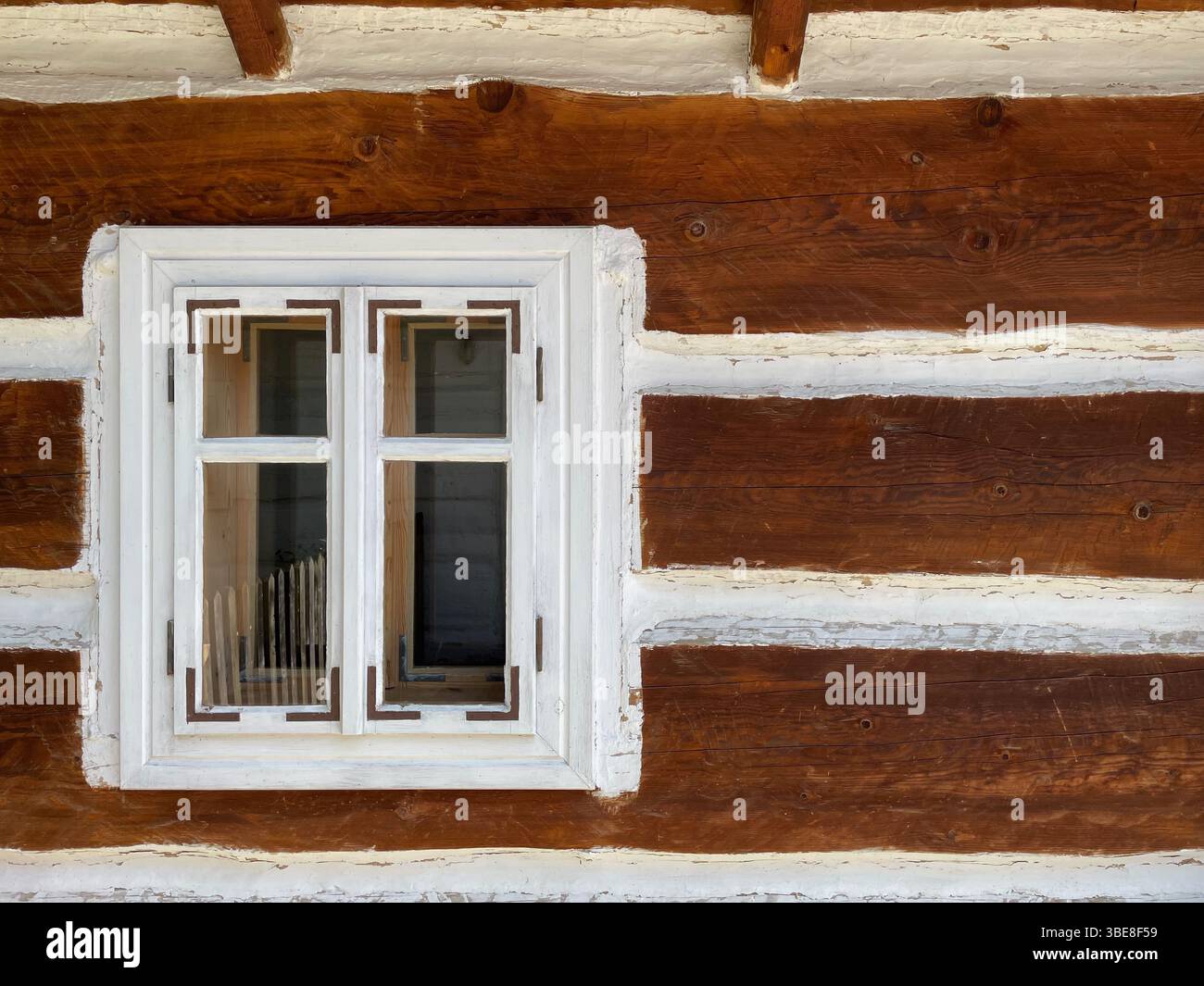 A window with white trim sits in front of a wooden wall. The window is ...