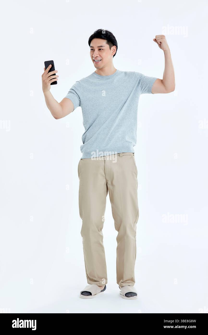 A young man staring at his phone screen, absolutely thrilled with his ...