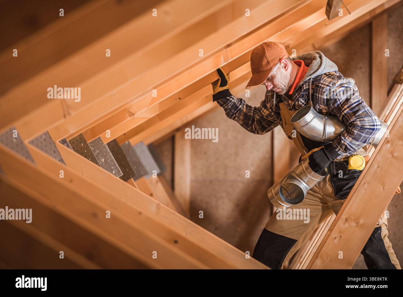 A skilled worker examines the wooden structure of an attic, wearing ...