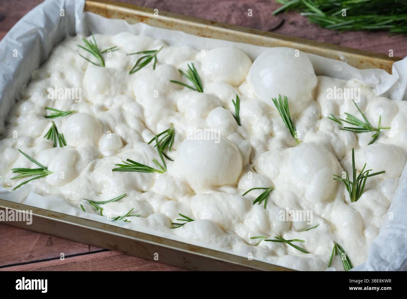 Fluffy bread dough rising in a rectangular pan lined with parchment ...