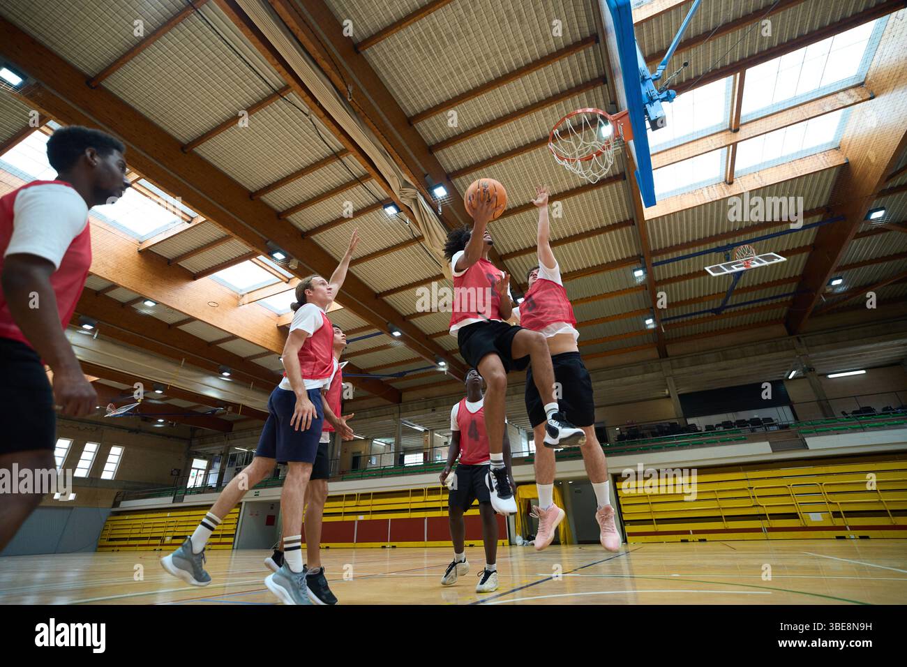 Basketball players jumping and shooting in a covered court Stock Photo ...