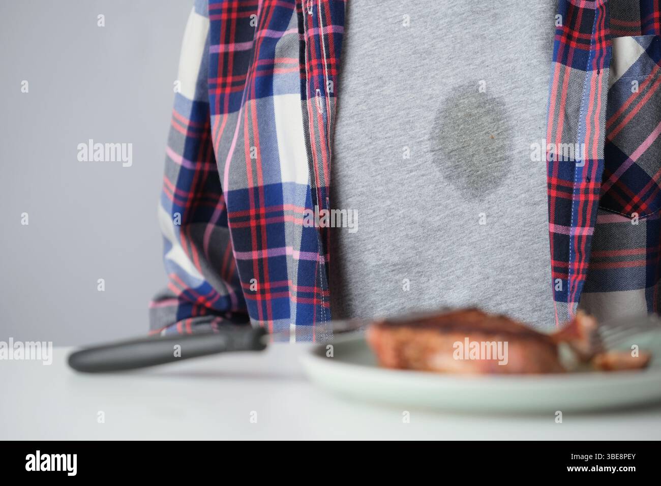 Tough grease stain on clothes. A person siting at a dining table, using ...